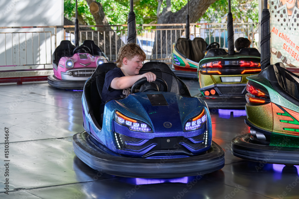 Teenage boy in dodgem bumper car, fun in sideshow alley, fun fair ...