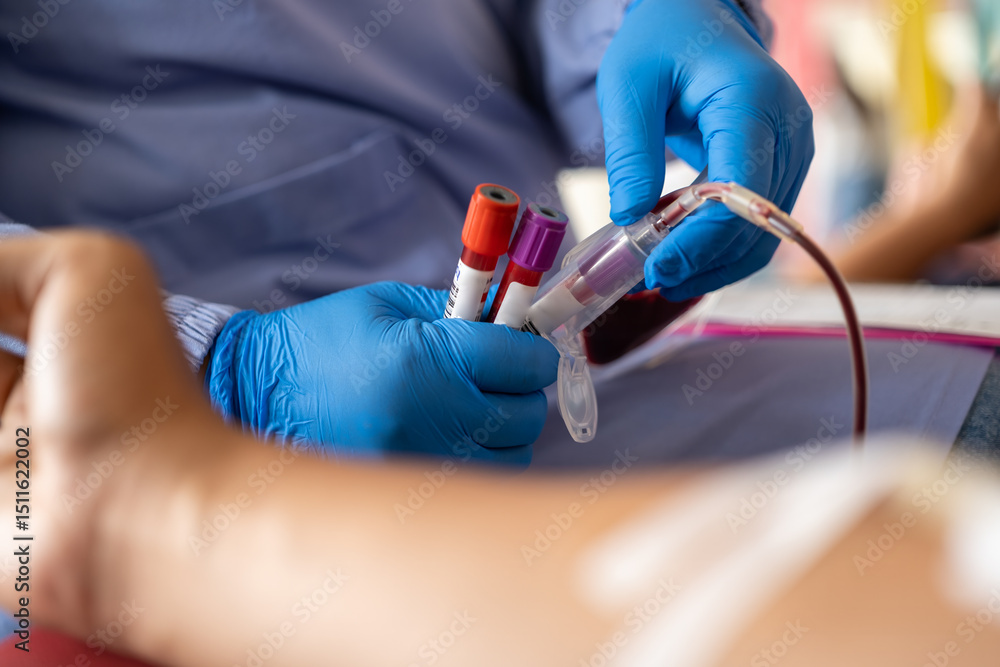 Close-up of a medical worker drawing blood into vials from a patient’s ...