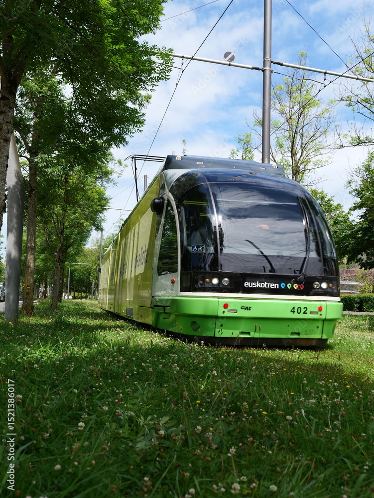 Bilbao Spain 05 06 2025 A modern green tram runs on grass-covered tracks in Bilbao, blending ...