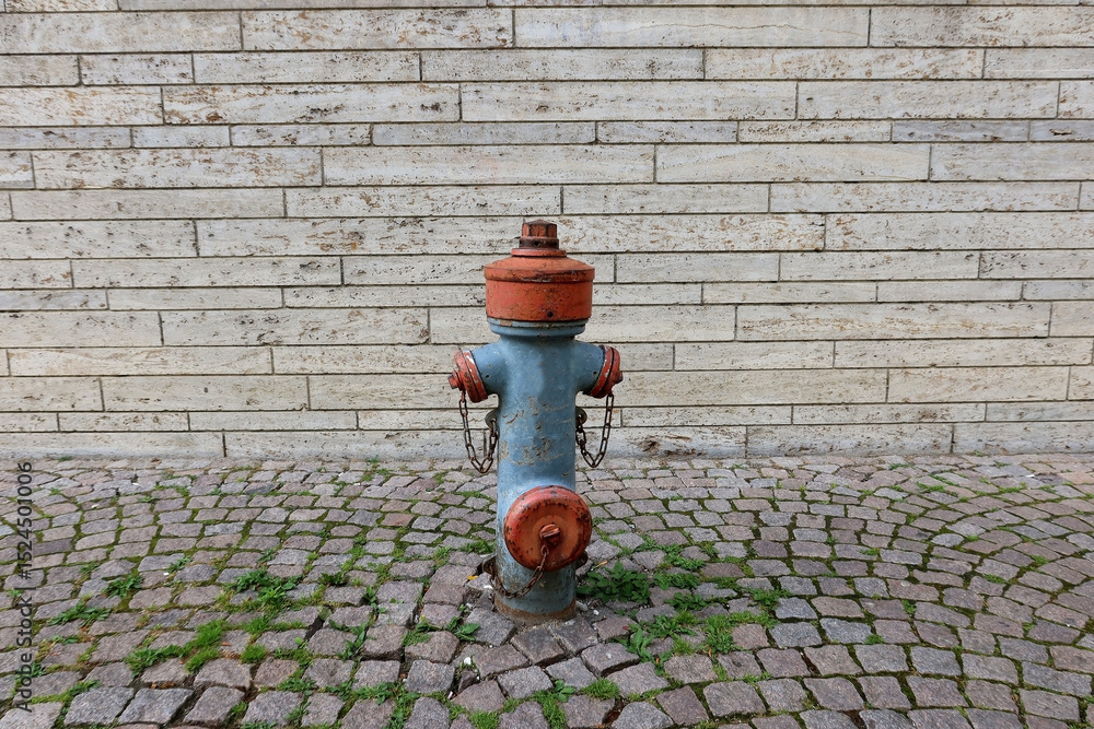 Old fire hydrant on cobblestone street in front of brick wall, vintage ...