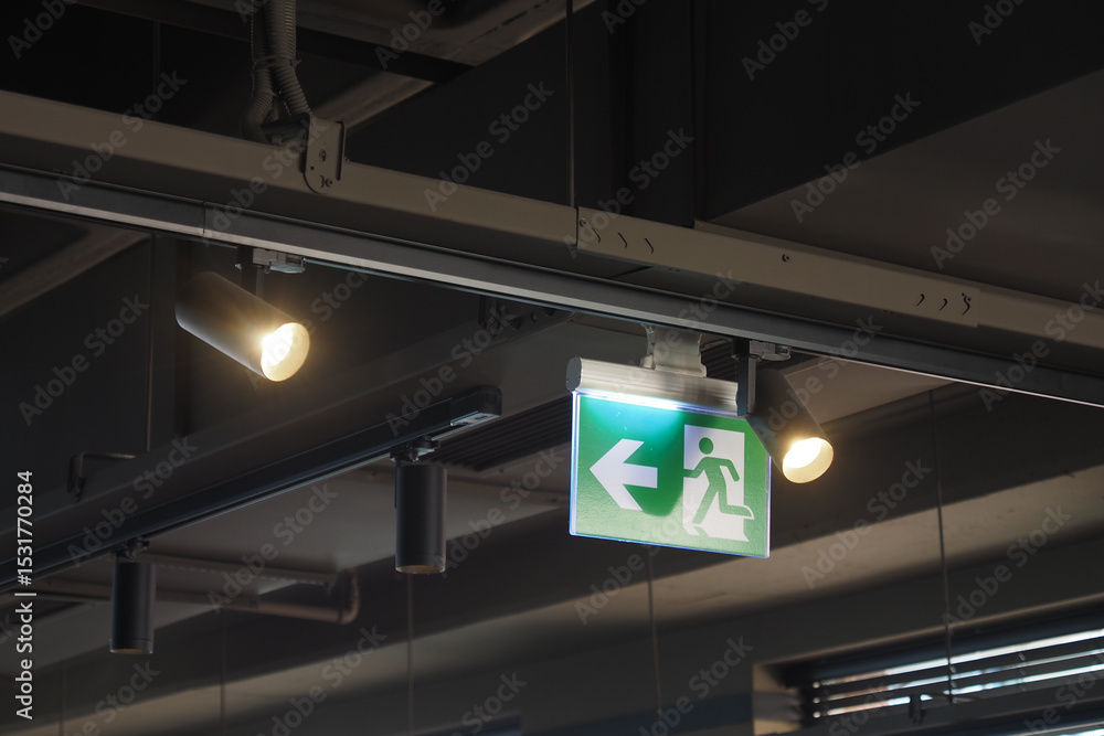 Emergency exit sign with directional arrow in a dim hallway Stock Photo ...
