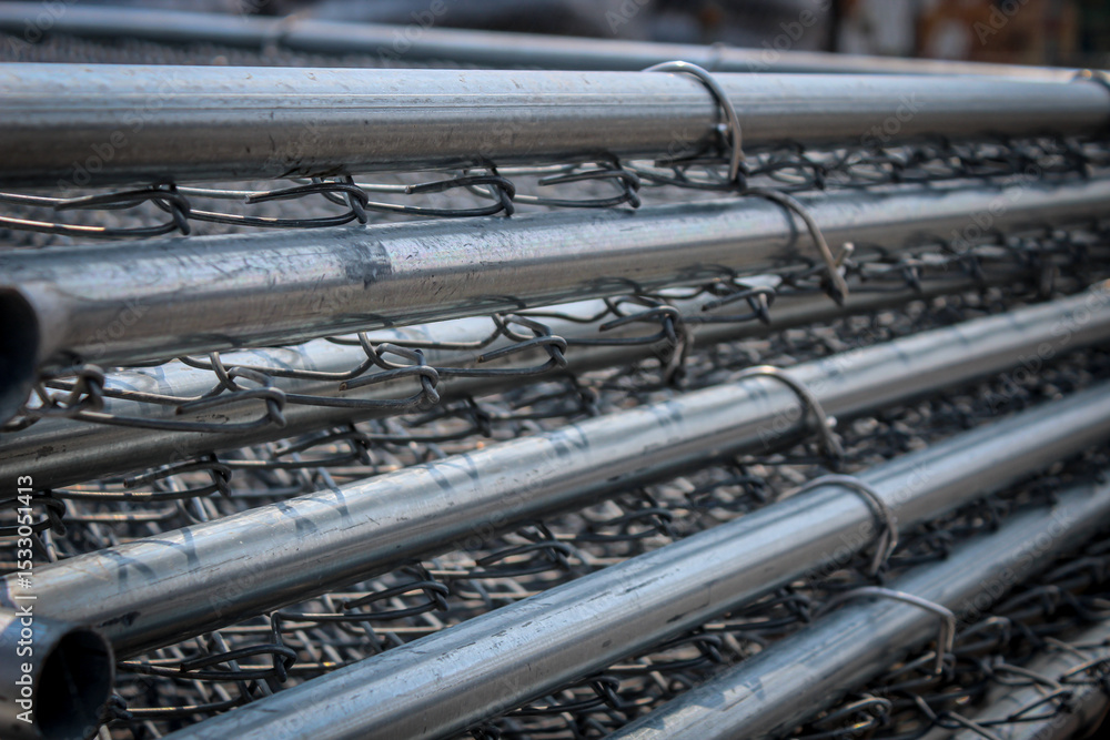 a tall stack of galvanized metal wire mesh fence panels ready for ...