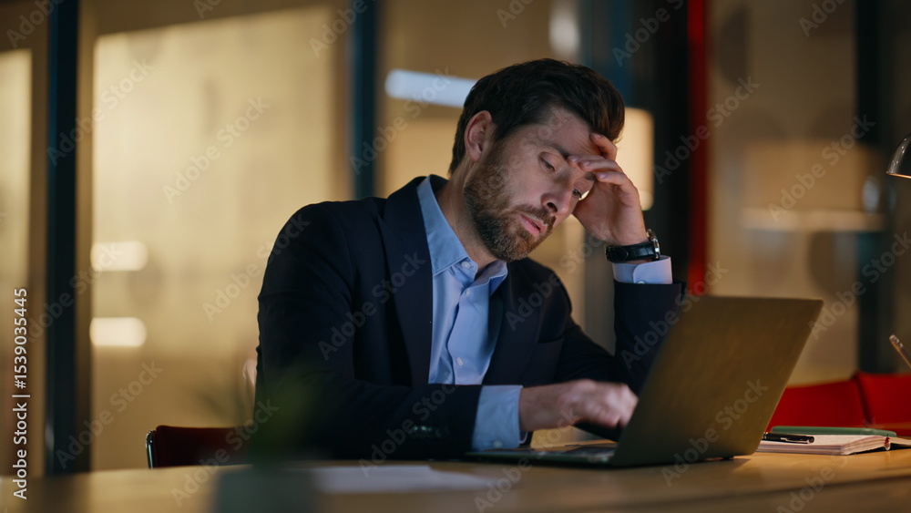 Overworked businessman typing laptop checking time at night office ...