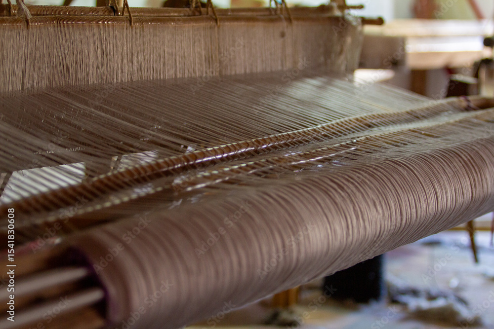 A close-up view of a traditional loom in action, showcasing intricate ...