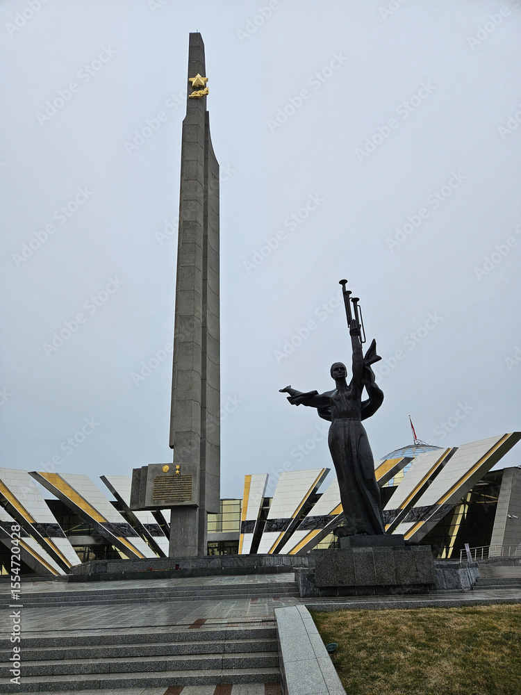 MINSK - MAR 26, 2025: A tall statue of a woman stands in front of a ...