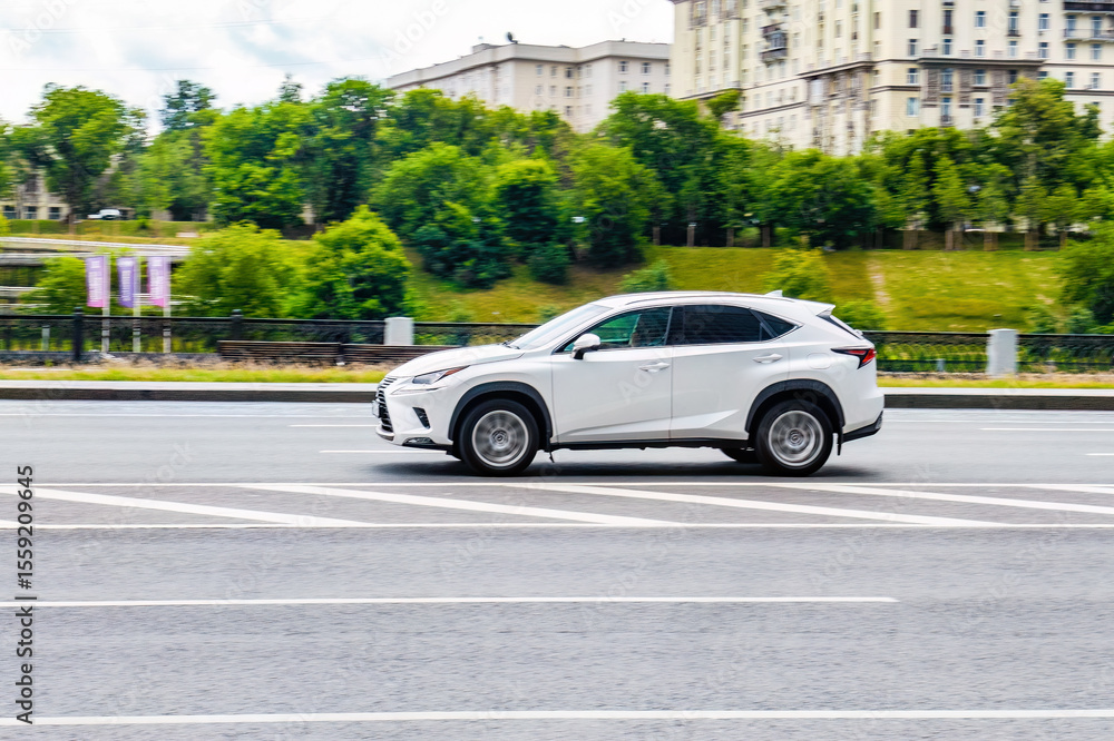 White Lexus NX car is moving on city street. Lexus NX 300h driving fast ...