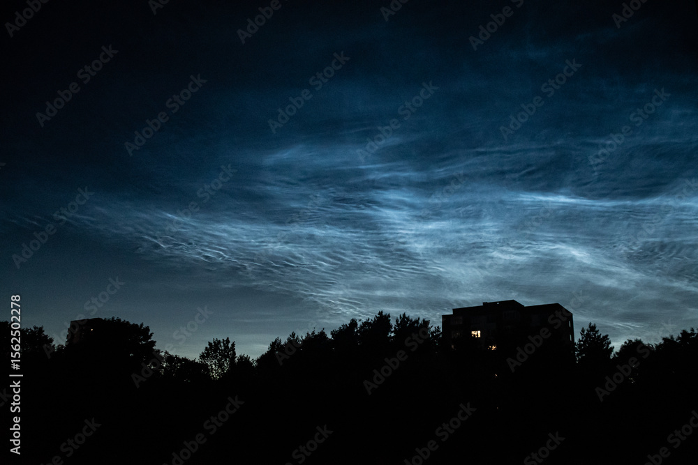 Noctilucent clouds glowing in the night sky above a silhouetted ...