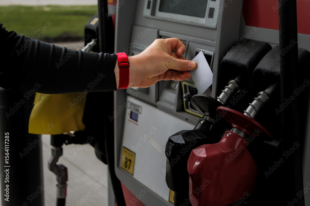 a person tapping a credit card onto a payment reader at a fueling ...
