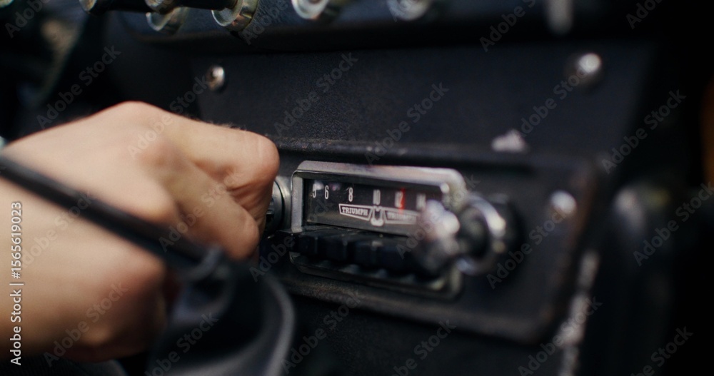 The man turns on the radio in the car, close-up of his hand as he turns ...