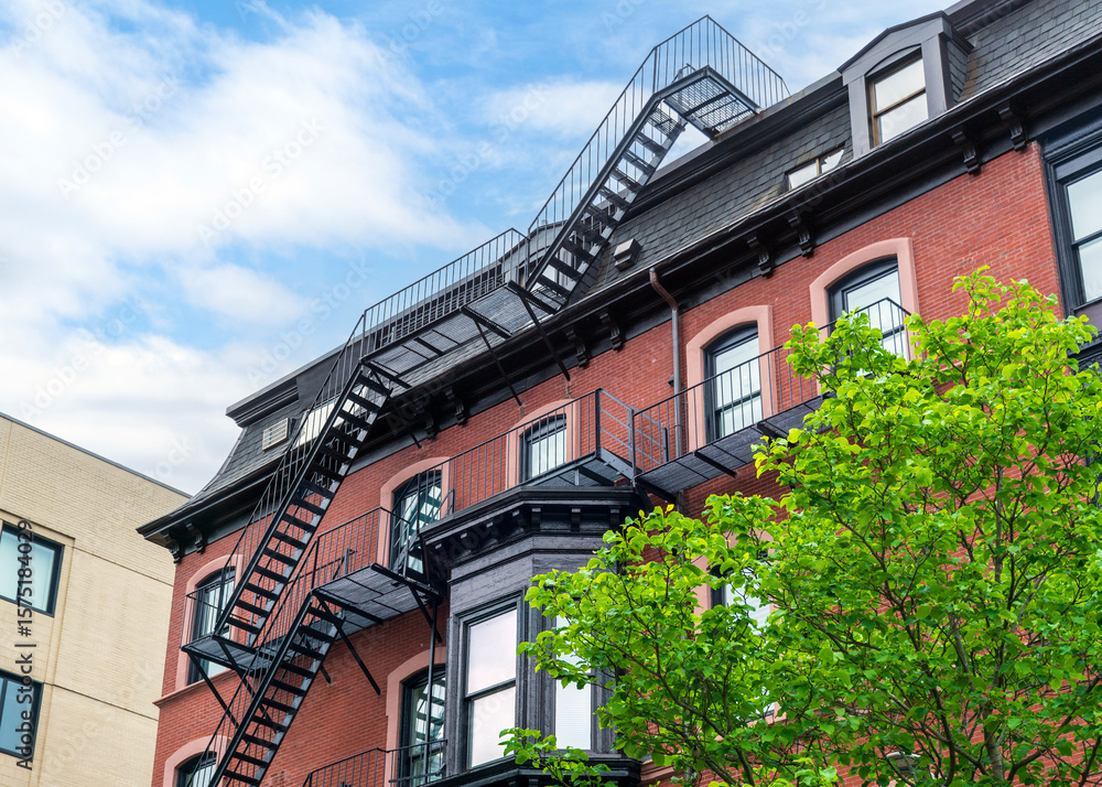 Historic red brick apartment building with black fire escapes and bay ...