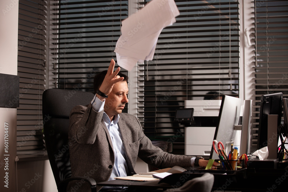 Frustrated businessman throws documents in the air, expressing stress ...