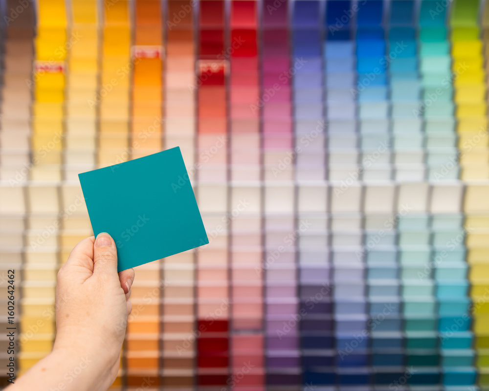 teal paint colour card held up in front of paint sample wall Stock ...