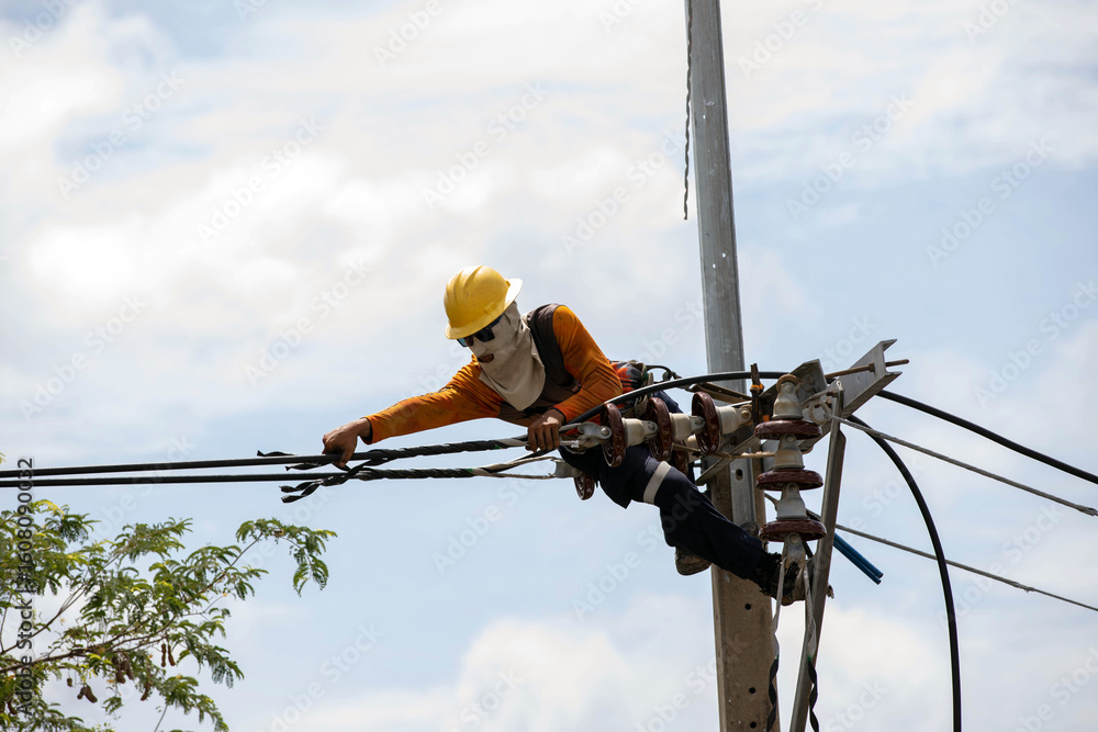 Electric utility worker repairing high-voltage power lines on a utility ...