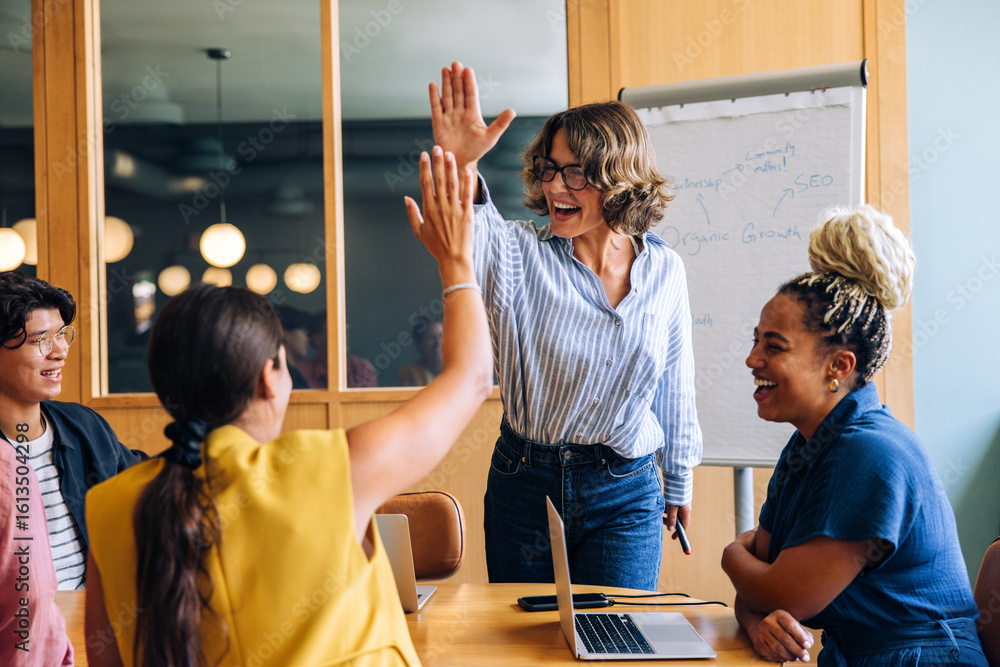 Group high-five during a successful meeting with enthusiastic team ...