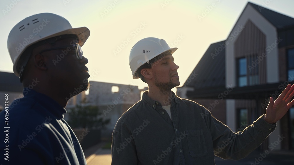 Two men in construction helmets are talking standing near the house ...