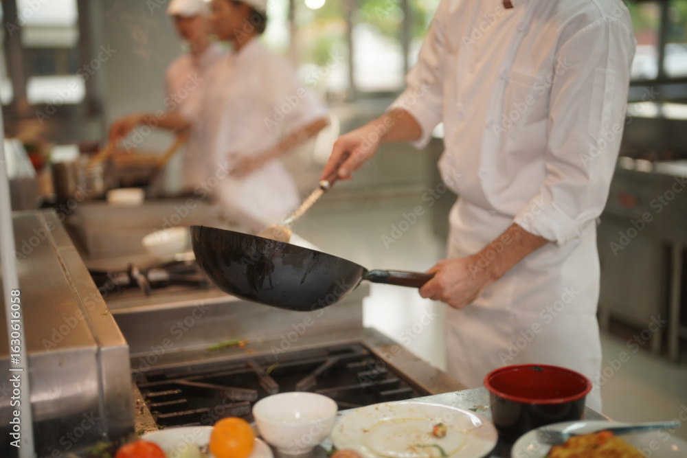 Cooks prepare dishes in a bustling kitchen during a busy lunch service ...