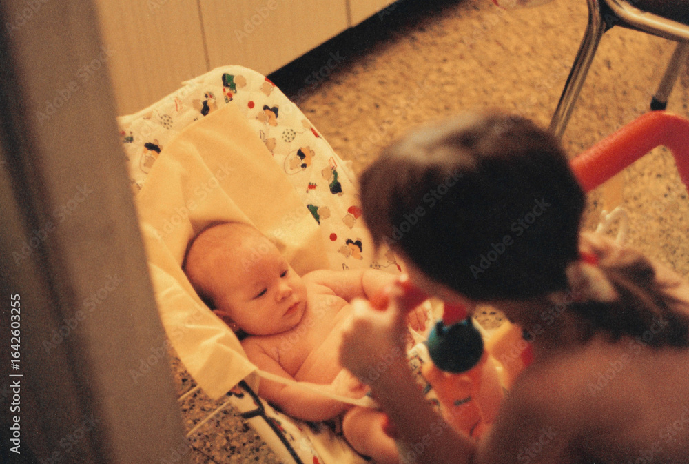 1990s analog photo of big sister caring for her baby sibling Stock ...