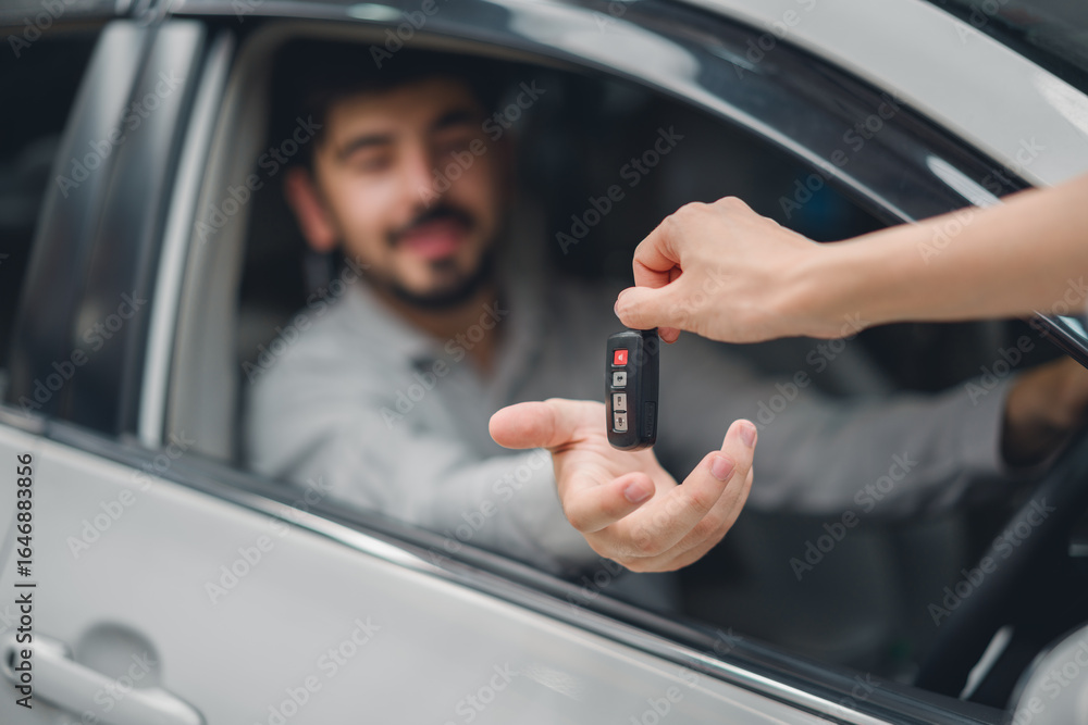 Car dealer giving key to new owner inside showroom, representing ...