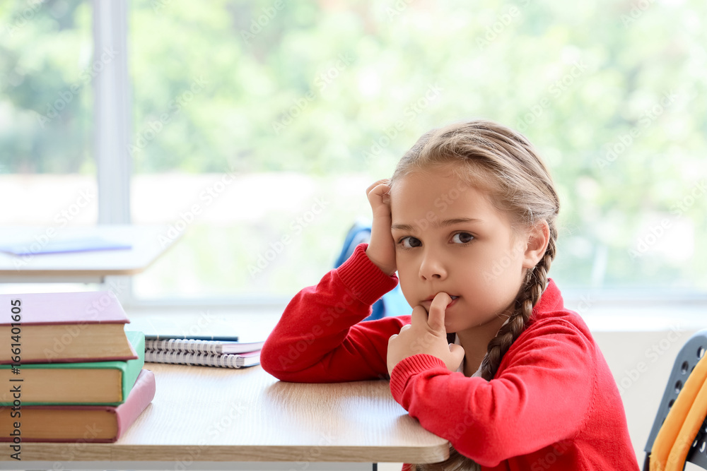 Little schoolgirl biting nails at desk in classroom Stock Photo | Adobe ...