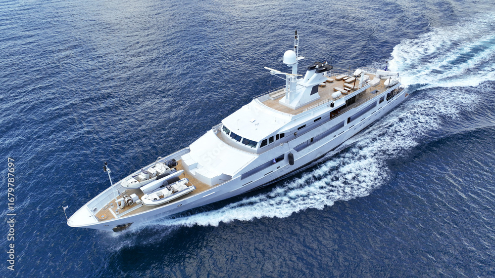 Aerial drone tracking photo of super yacht with wooden deck cruising ...