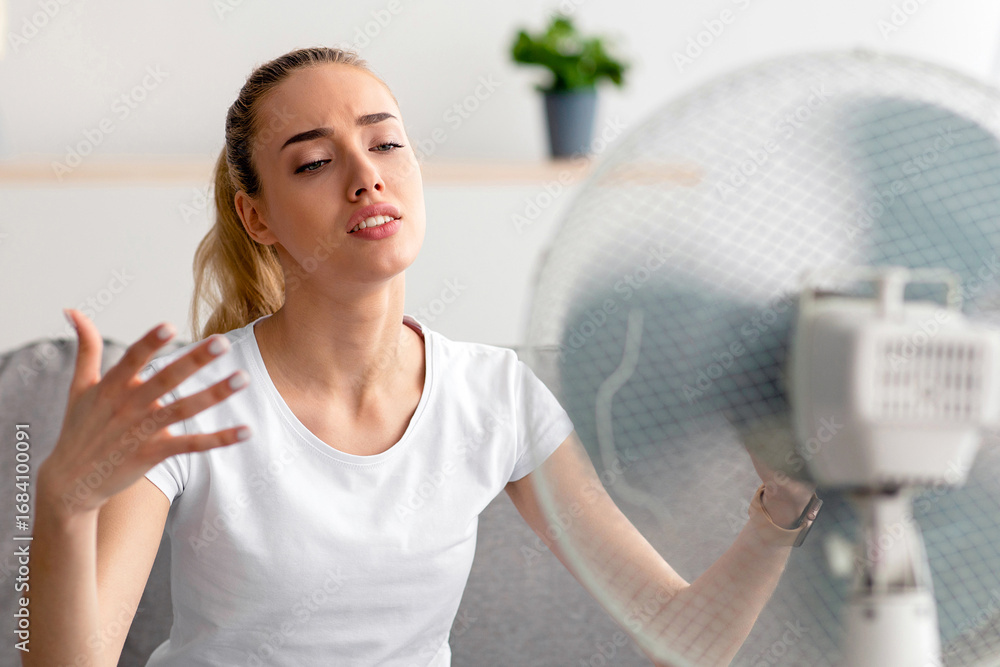 Mature woman cooling herself in front of fan during hot weather. Tired ...