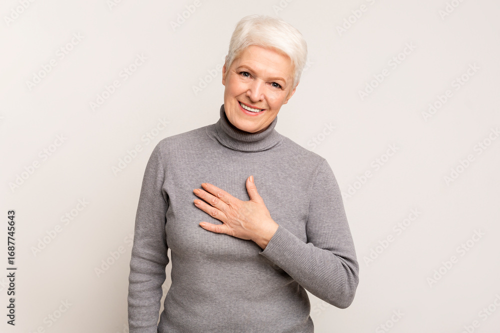 Thankful senior lady keeping hand on her chest chest, express gratitude ...