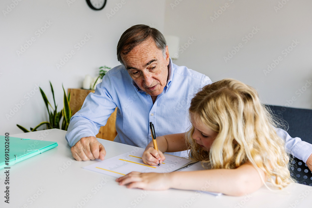 Young little cute girl doing homework with her grandfather at home. Old ...