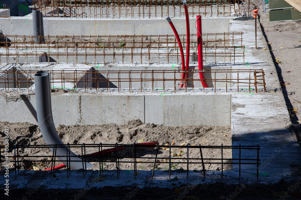 Construction site featuring concrete foundations with exposed rebar and ...