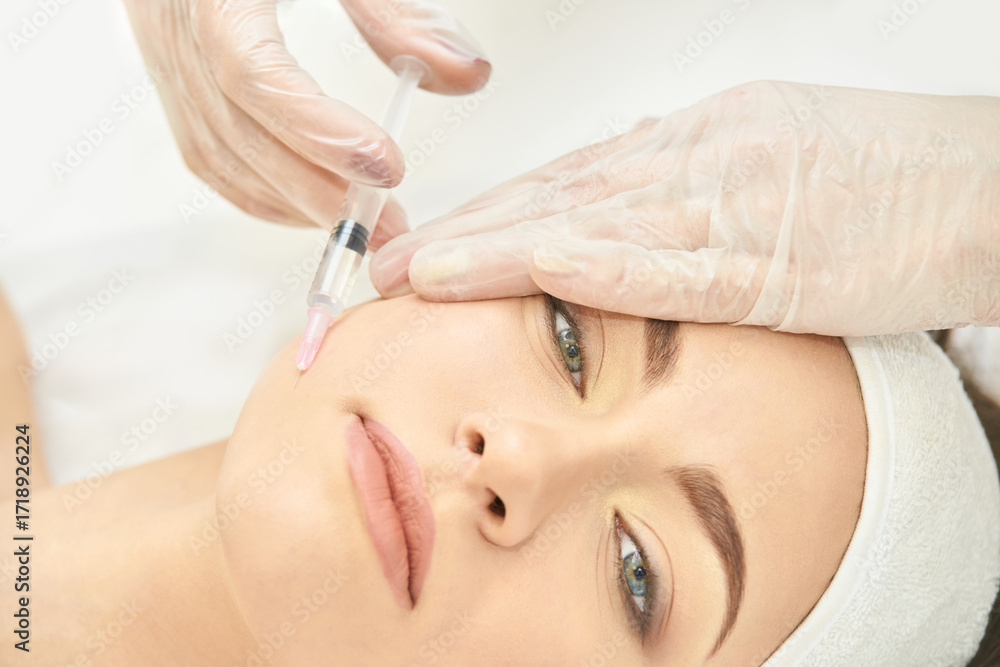 Female receiving facial injection treatment with gloved hands in ...