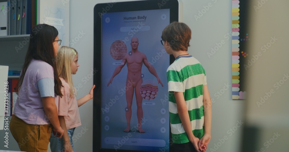 Kids Study Human Body on Interactive Screen. Two Girls and Boy Interact ...