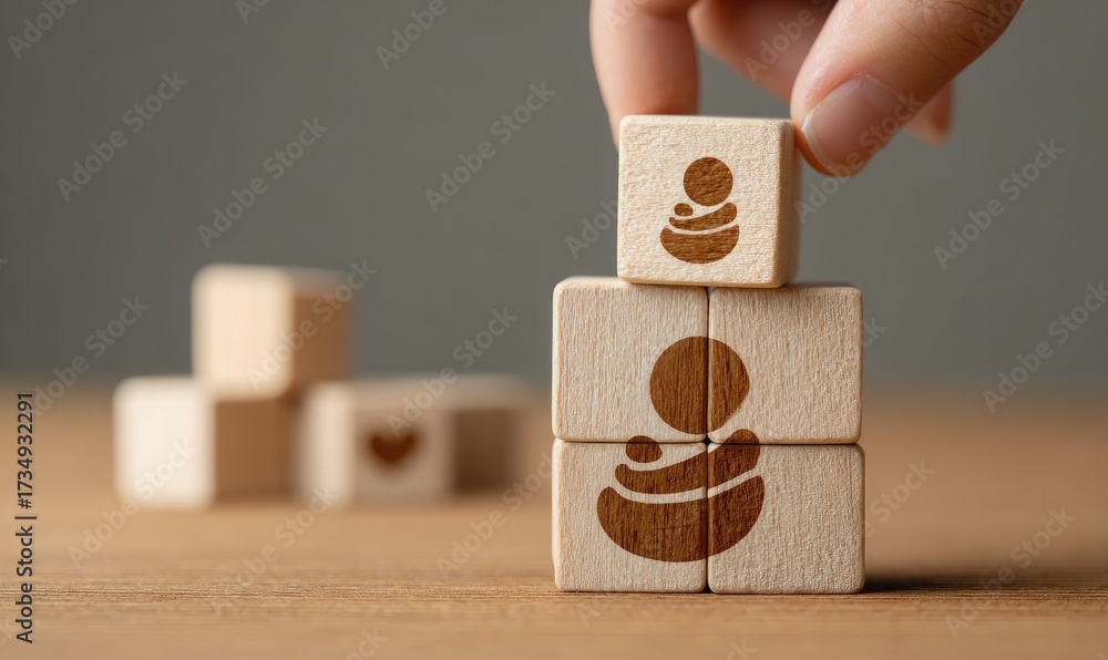 Wooden blocks with engraved family symbols are being stacked. A hand ...