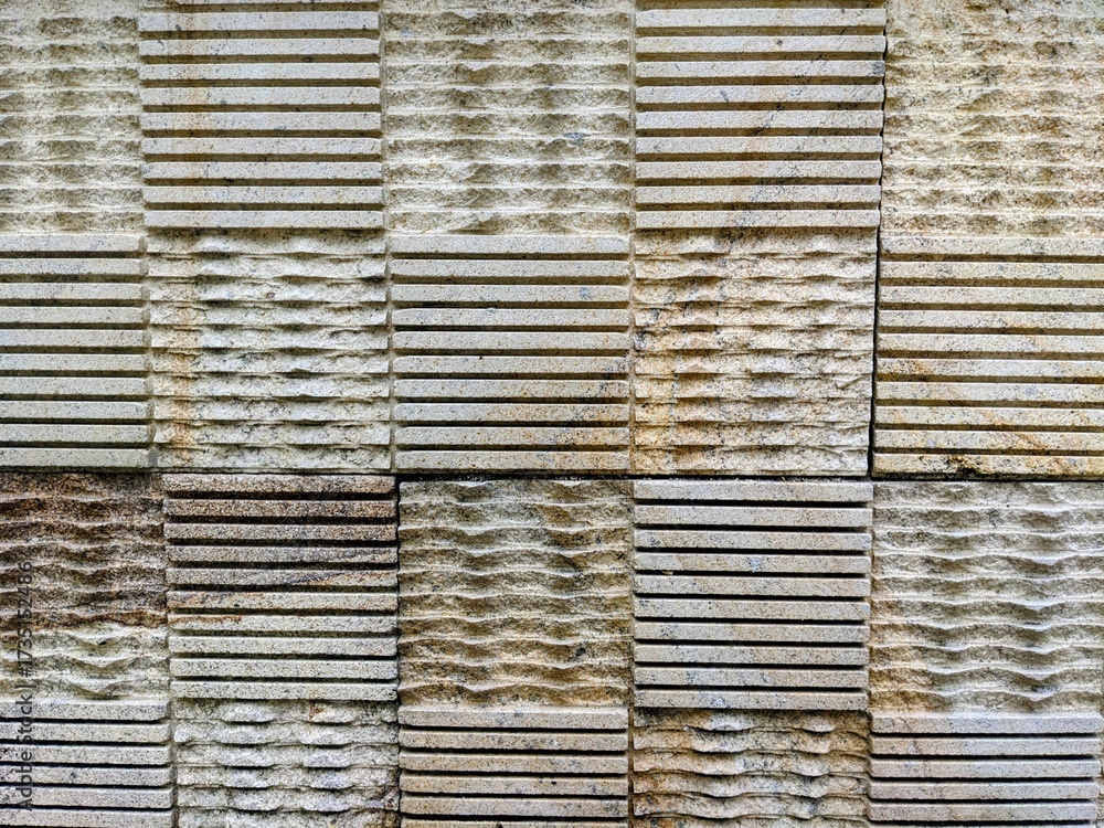 Textured stone wall cladding features alternating panels of horizontal ...