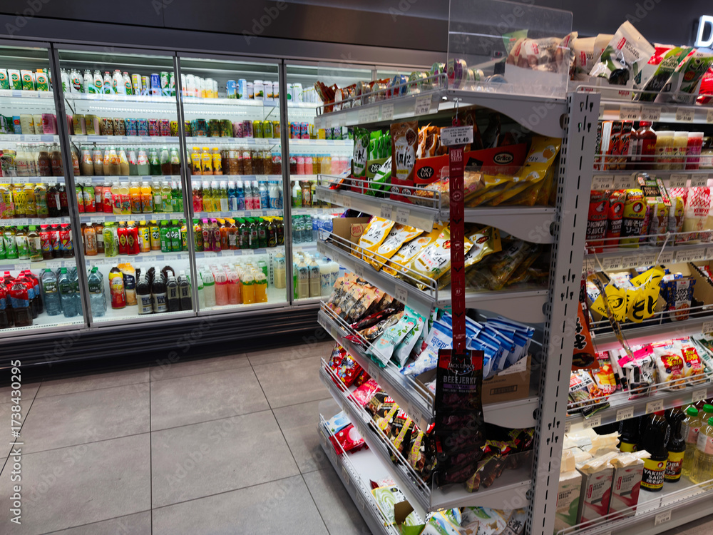 Bright supermarket aisle with refrigerated beverages and snack shelves ...
