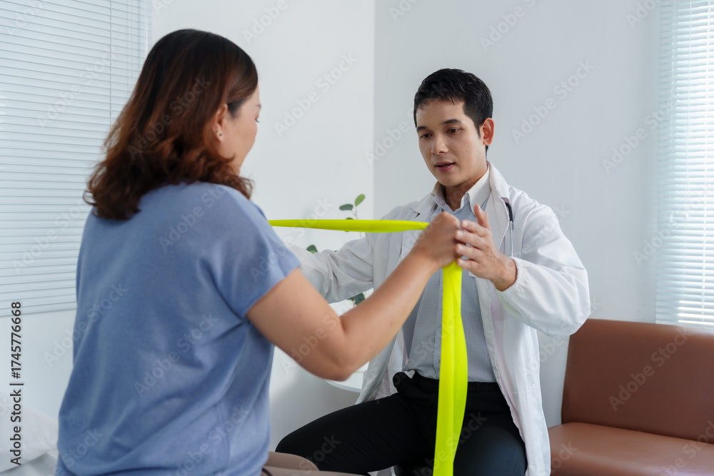 Doctor guiding female patient through arm exercises using a resistance ...