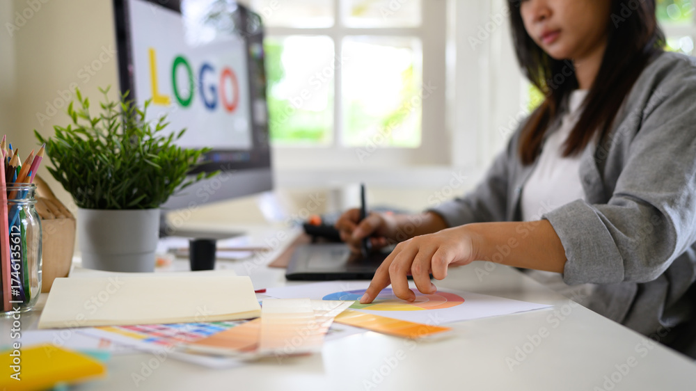 Designer hand pointing at color chart and drawing on tablet, focusing ...