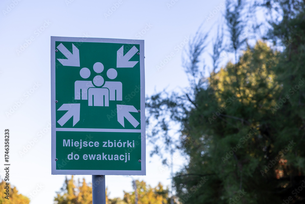 Green emergency assembly point sign with white people icon and arrows ...