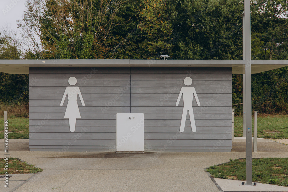 Public restroom building with male and female symbols on a wooden ...