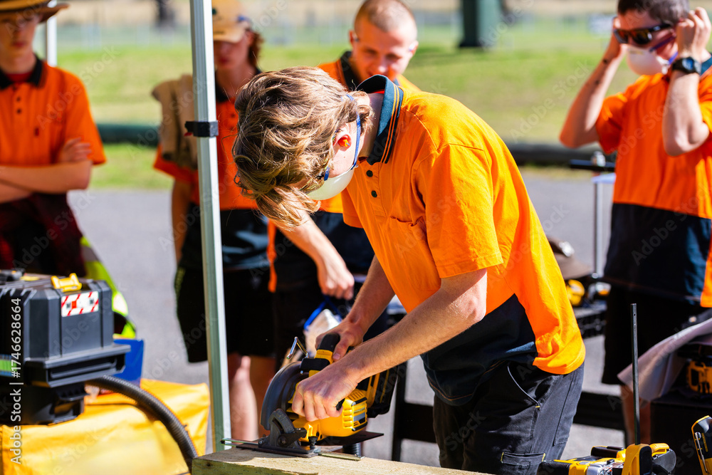 Teenaged trade apprentice using circular saw tool to cut wood during ...