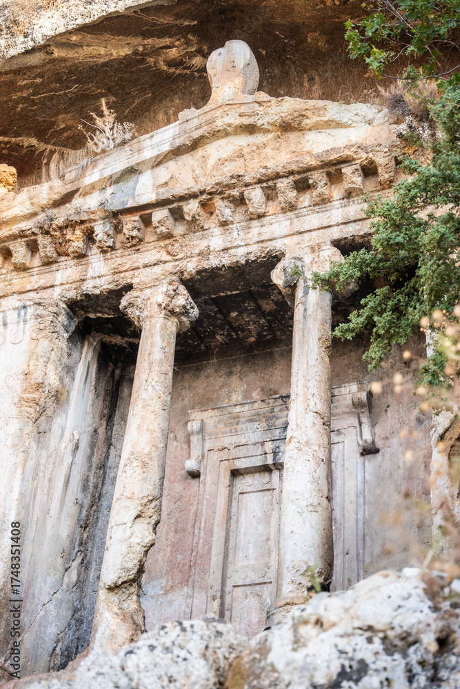 ภาพถ่าย Stock Ancient rock-cut tomb with columns and worn stone facade ...