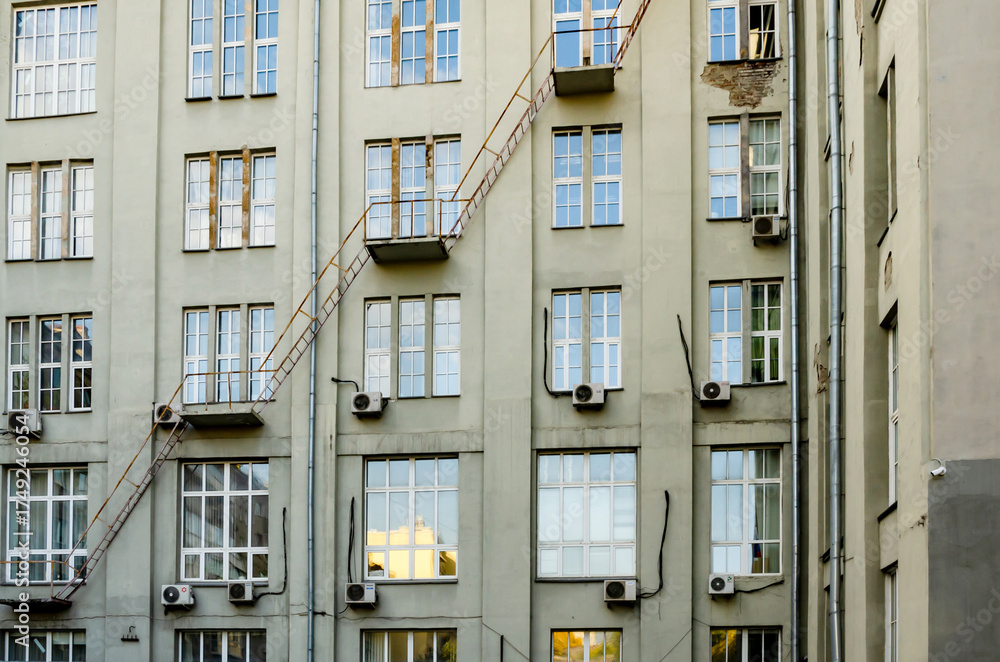 Metal fire escape ladder attached to exterior wall of aged multi-story ...