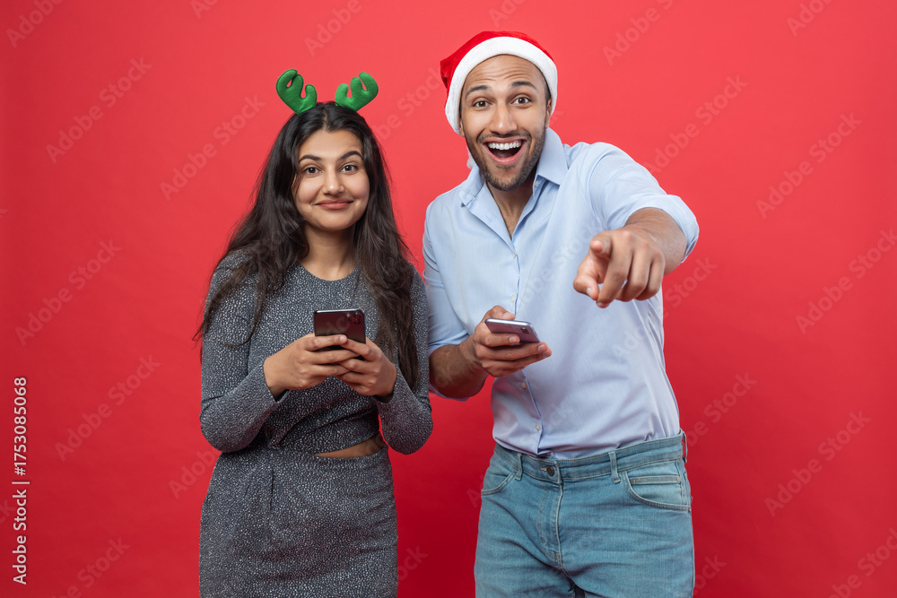 Couple in Santa hats using phones to share holiday greetings and ...
