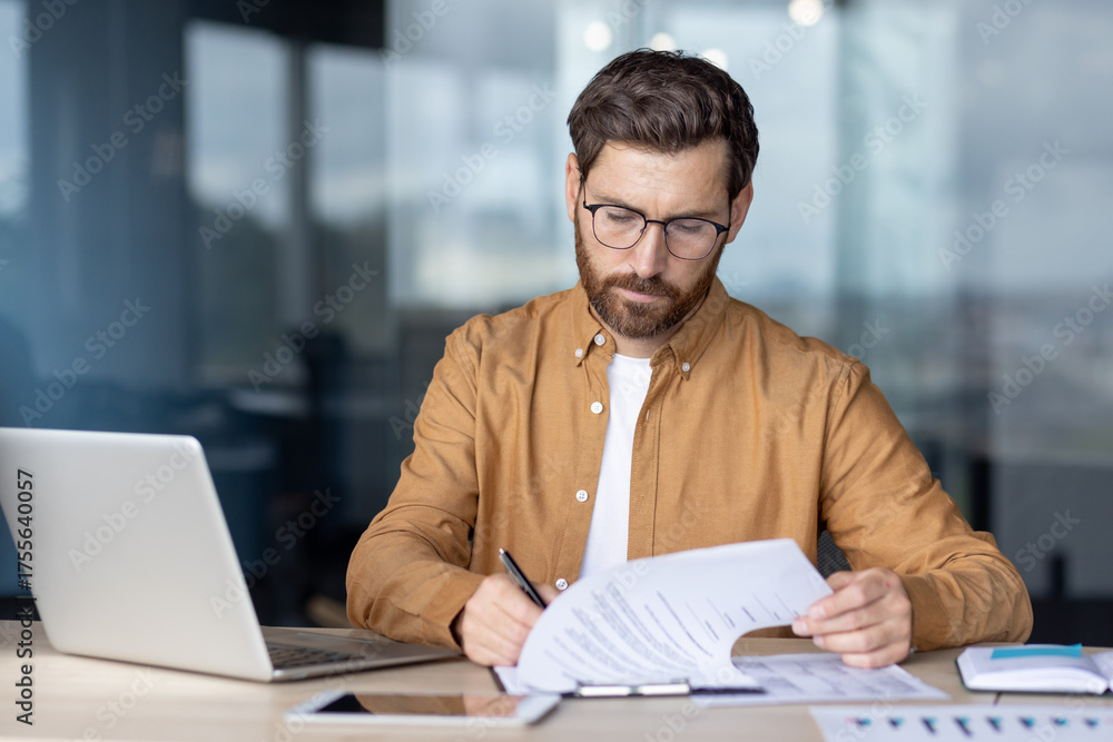 Confident focused businessman working on paperwork while sitting at a ...
