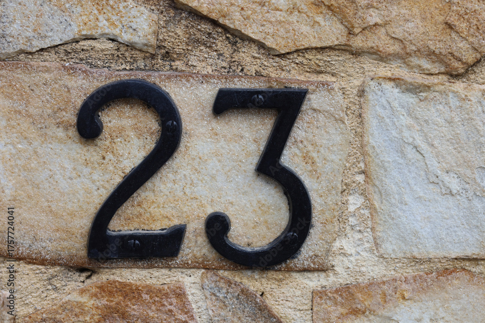 House number twenty three. Black figures of two and three on old brick ...
