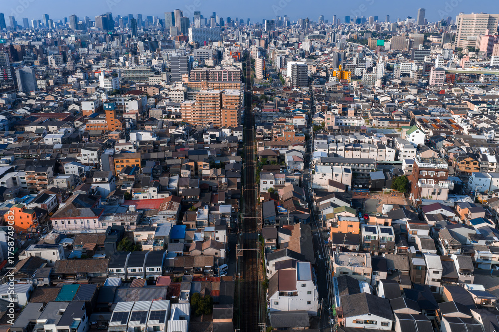 Aerial view shows a straight rail line through low rise homes toward ...