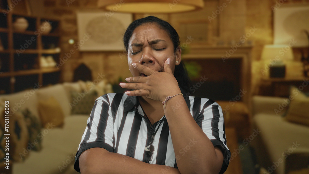 Woman referee wearing a black and white striped uniform rests her chin ...
