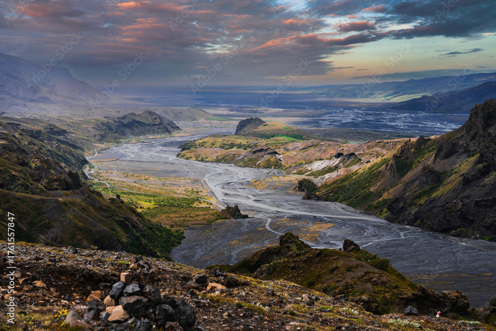 Braided glacial rivers cross a valley in Iceland at dusk, with volcanic ...