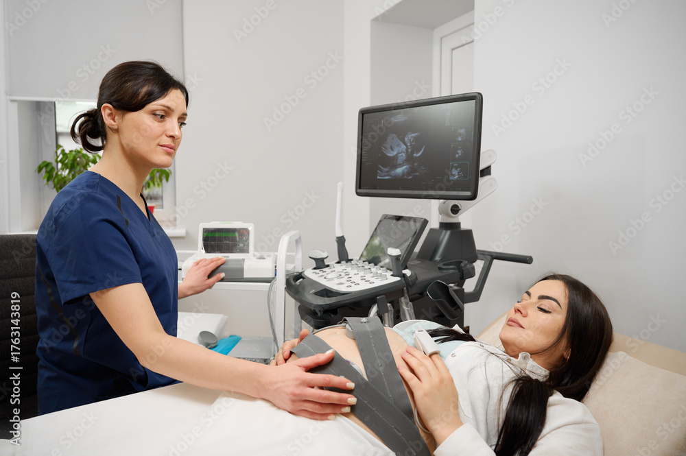 Pregnant woman undergoing cardiotocography procedure. CTG procedure to ...