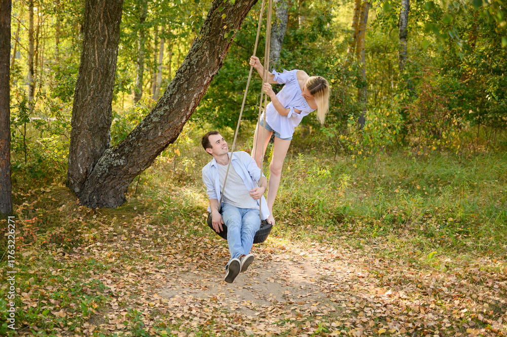 Family vacation outdoors. Man in love swings with girlfriend on tire ...