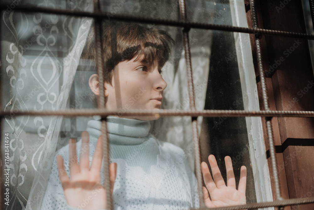 Poor sad orphan girl looking out of window. Stock Photo | Adobe Stock