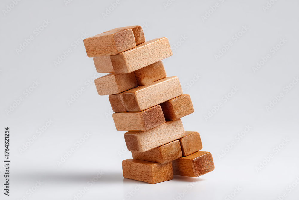 Precariously stacked wooden blocks, a tower built on balance, tilting ...